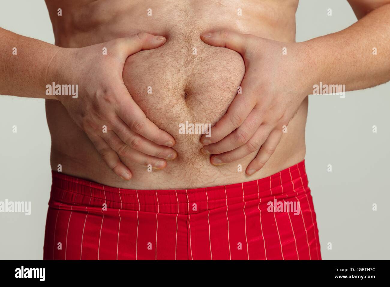 Close-up fat male abdomen, belly isolated on gray studio background ...