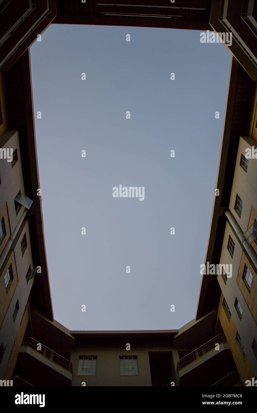 Vertical low angle shot of a neighborhood of buildings in a rectangular shape with the sky above ...