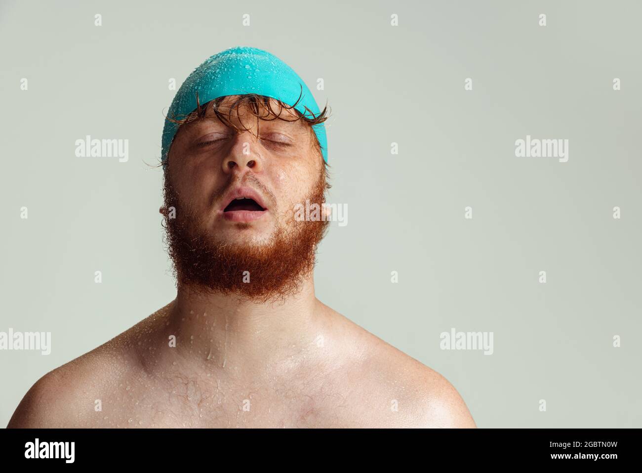 Close-up image of red-headed man in swimming hat posing isolated on ...