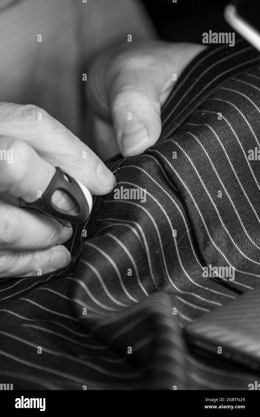 Grayscale Close up hands of seamstress at work. sewing suit pants with ...