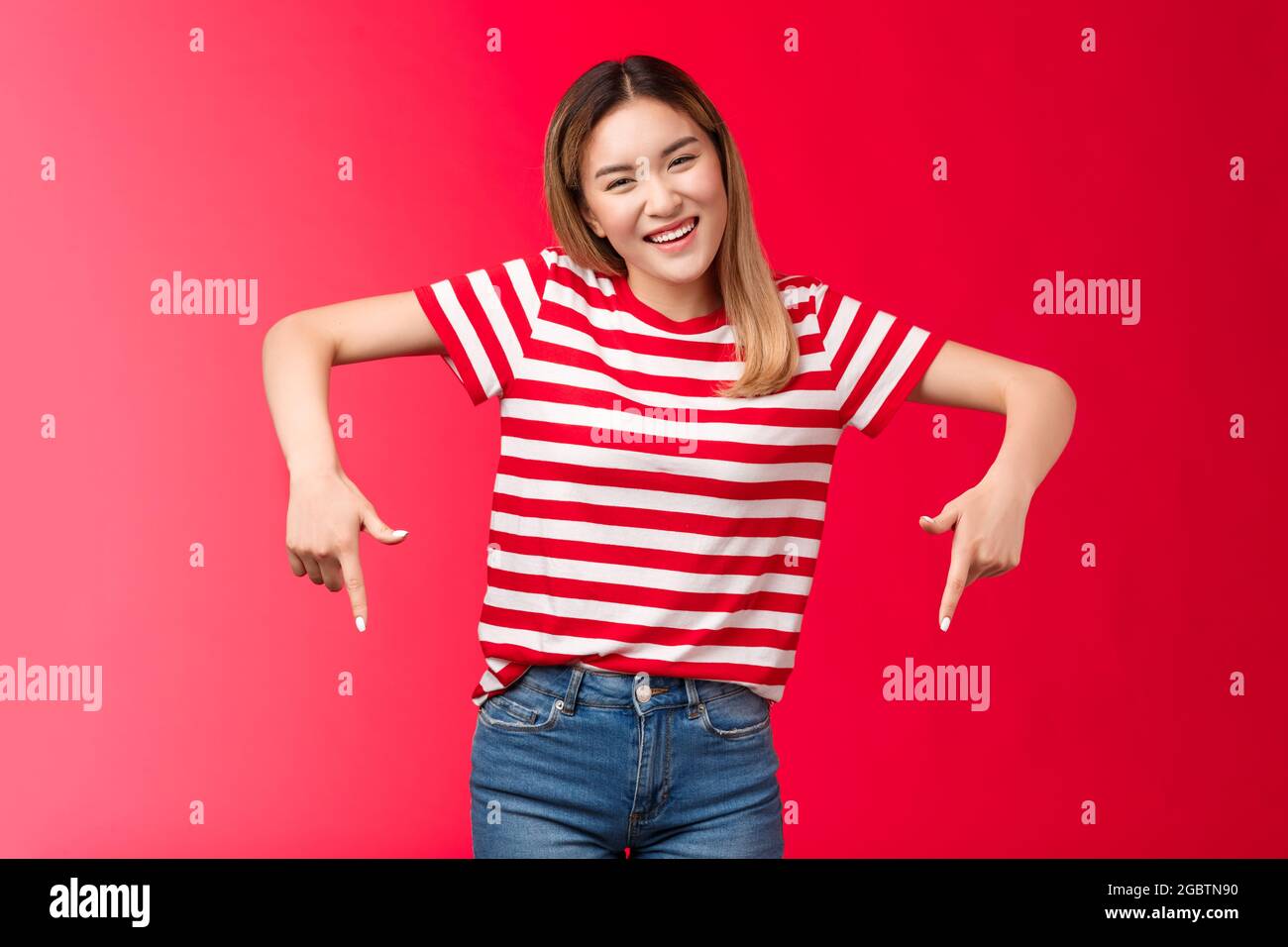 Friendly outgoing attractive blond asian girl pointing down show index ...