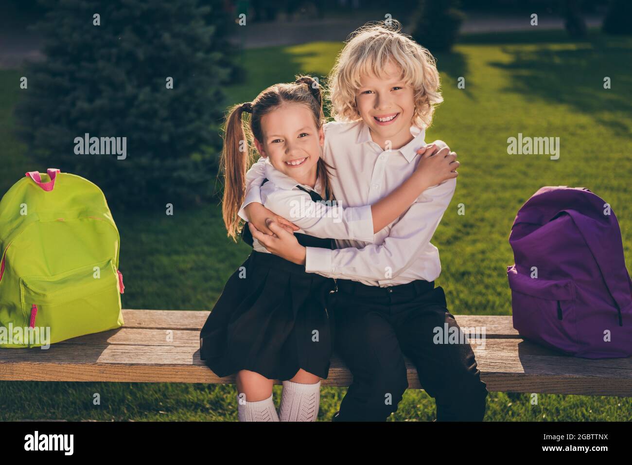 Photo of classmate friendly kids sit bench embrace each other wear ...