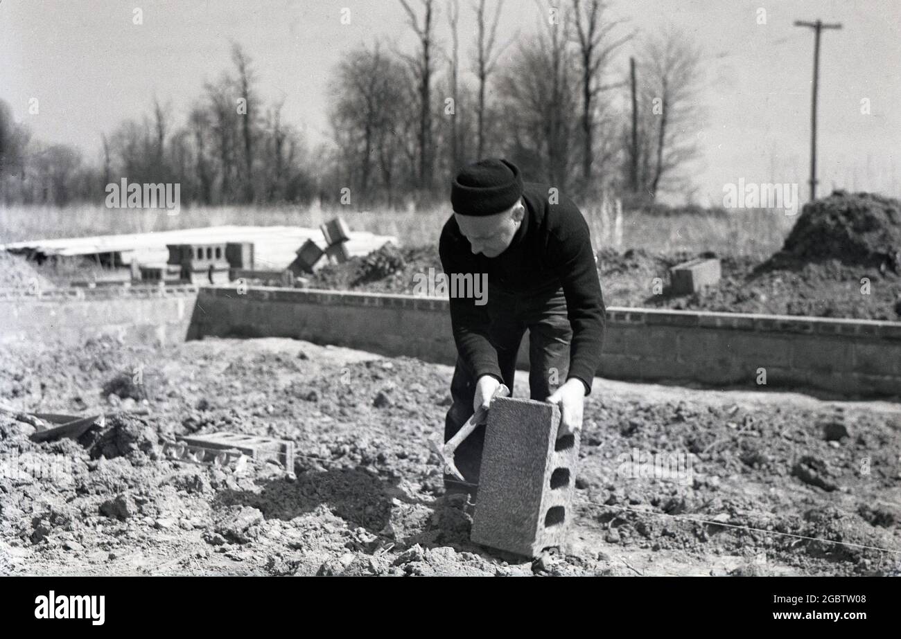 1950s, historical, on a domestic construction site, a builder with a ...