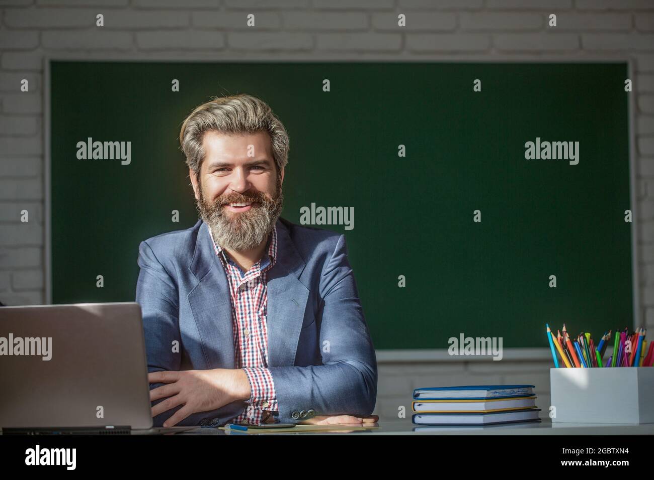 Portrait of confident male teacher in classroom. Young male teacher ...