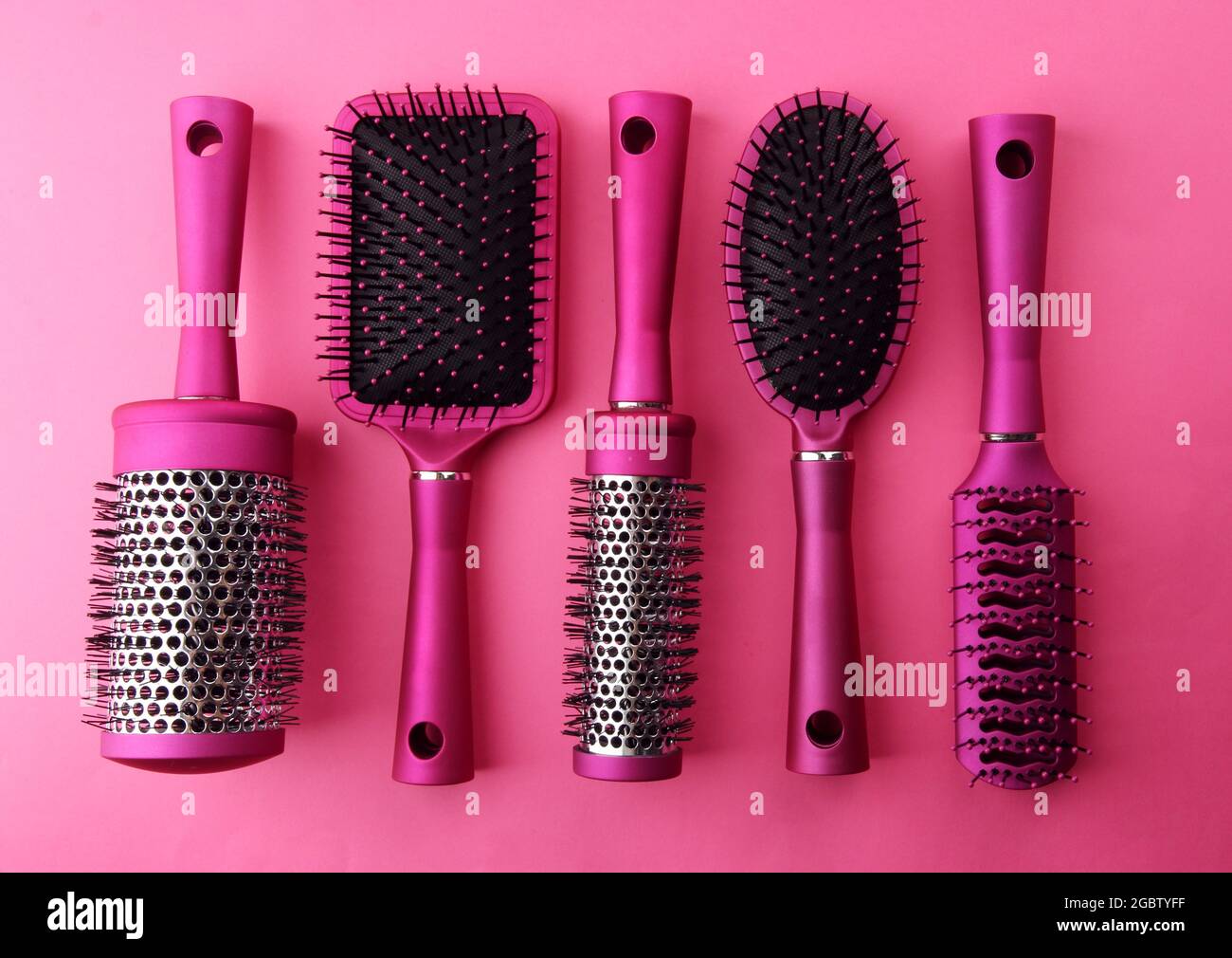Comb brushes on pink background Stock Photo - Alamy