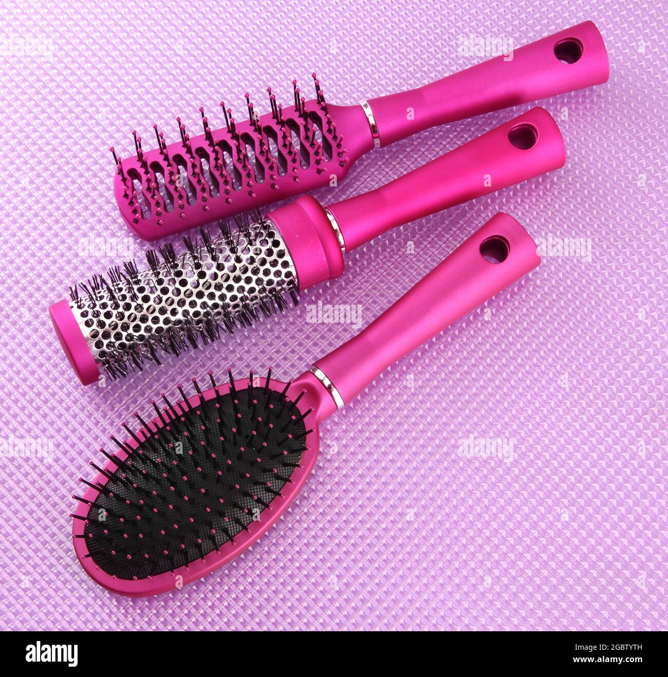 Comb brushes on purple background Stock Photo - Alamy