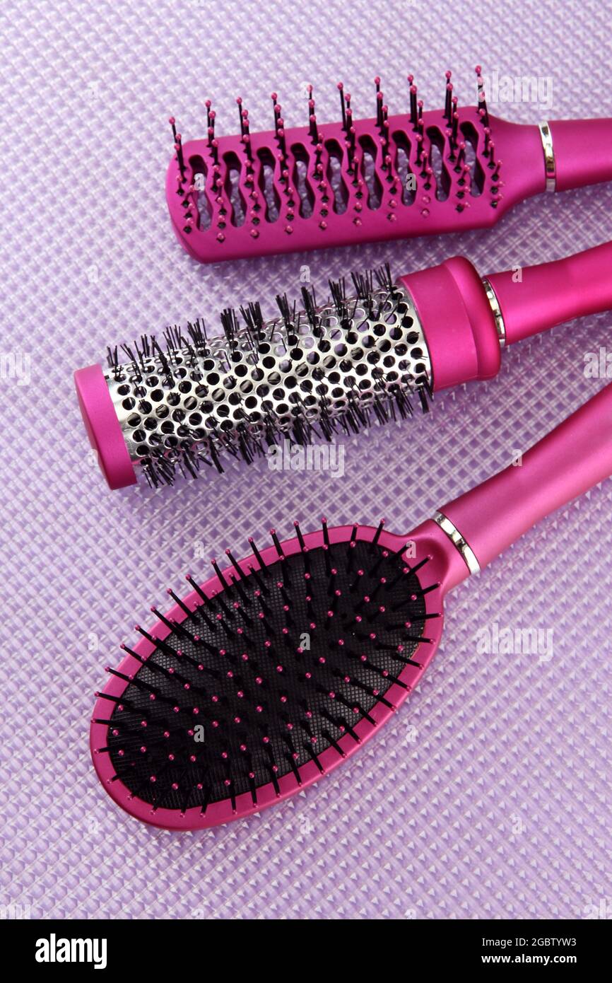 Comb brushes on purple background Stock Photo - Alamy
