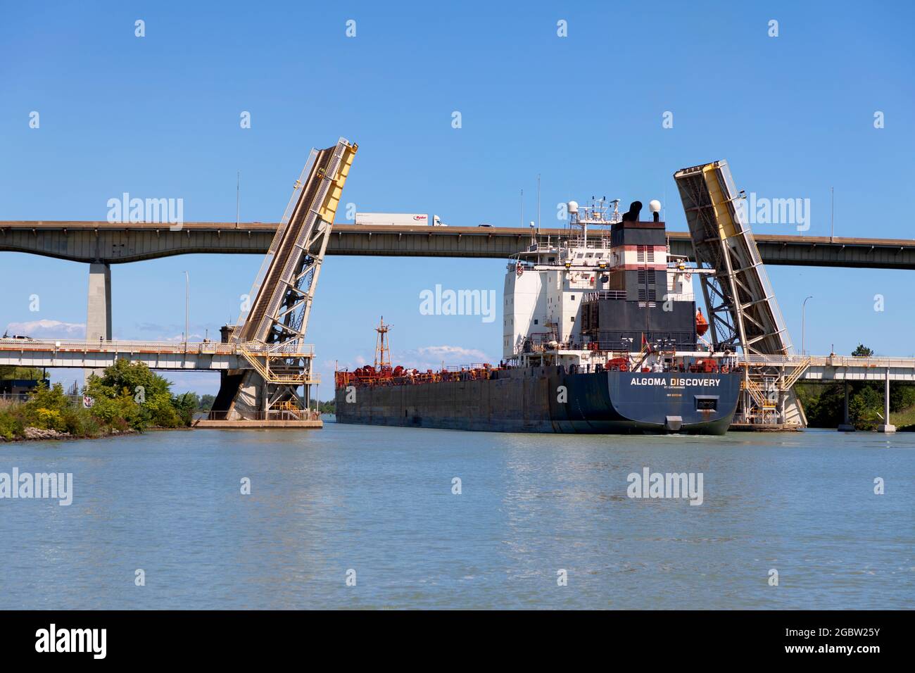 Freight ship passing under Queen Elizabeth Way Garden City Skyway and ...