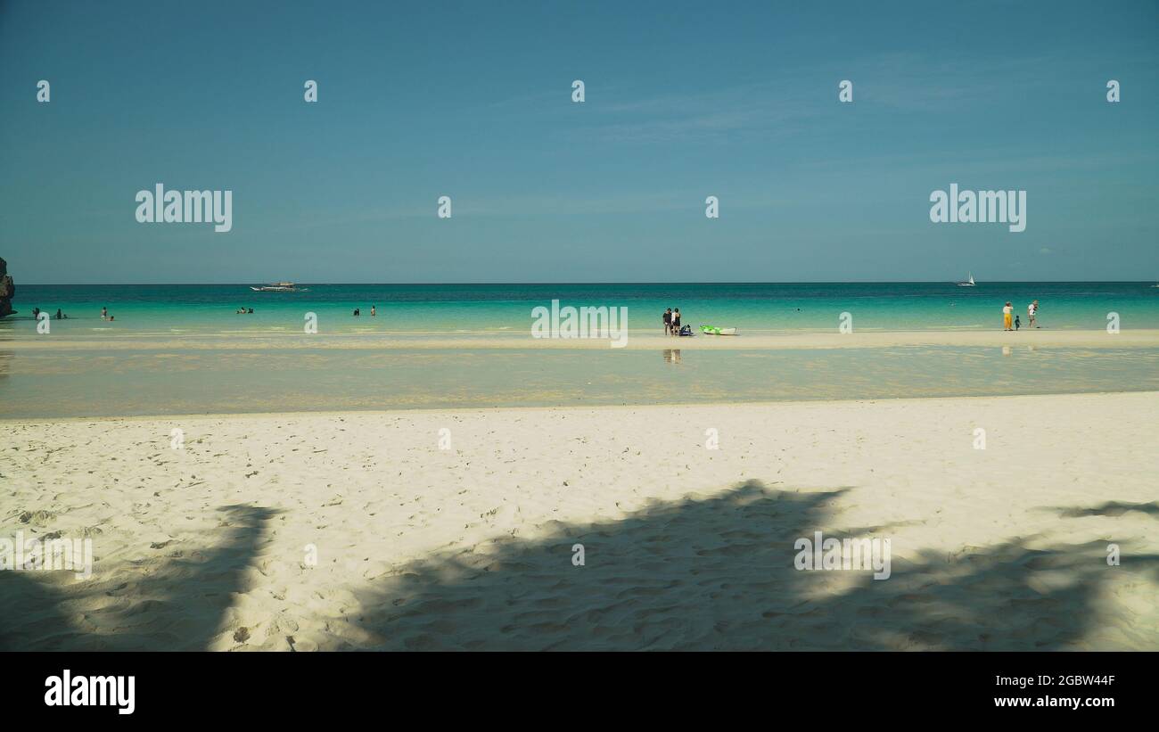 Tropical beach with tourists and clear blue sea. Summer and travel ...