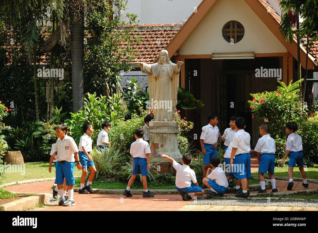 A group of elementary students play together around a Jesus statue in ...