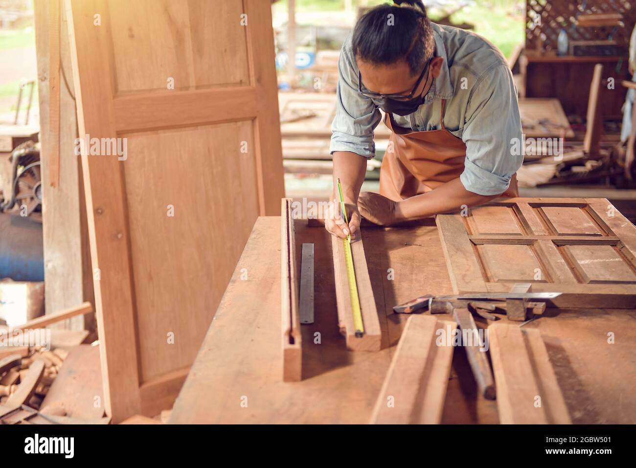 Close-up of a hardworking carpenter holding a angular ruler and pencil ...