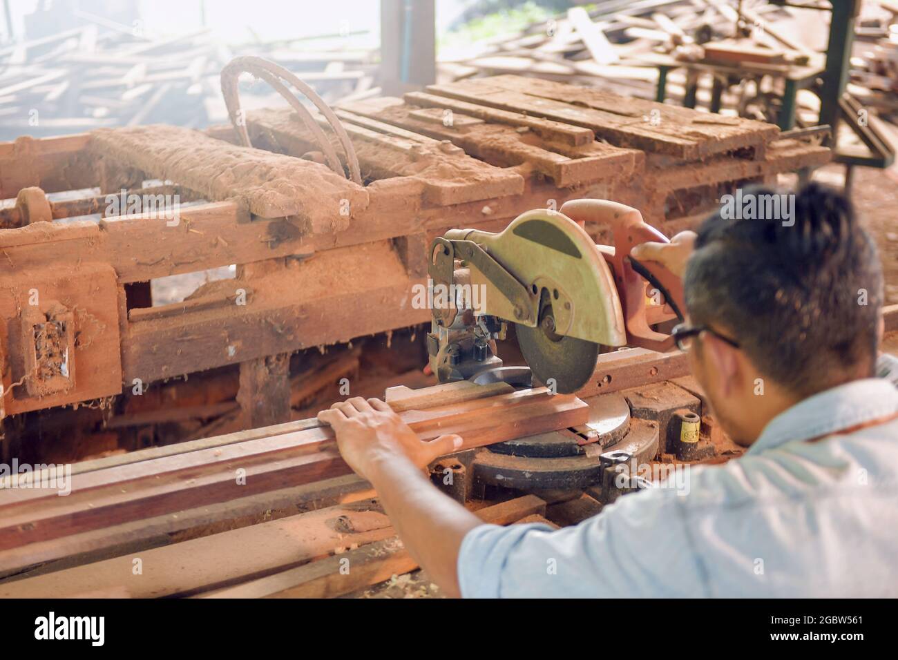 Skilled carpenter cutting a piece of wood in his woodwork workshop ...