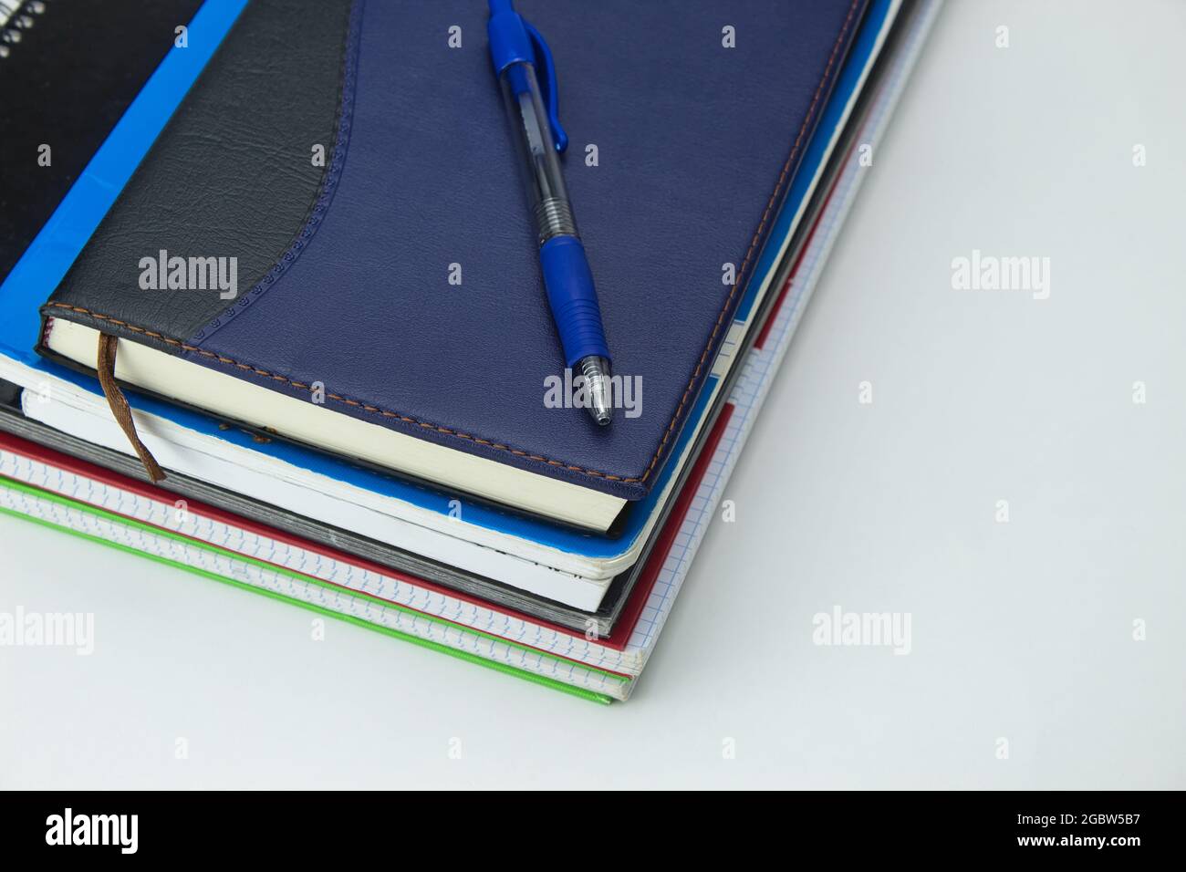 stack of notebooks and diaries with a blue pen on the top on a white ...