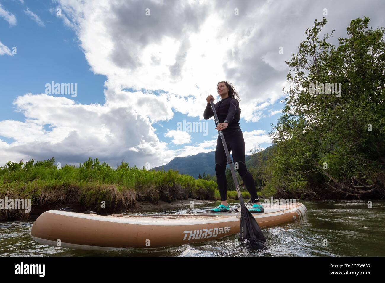 Adventurous people paddle boarding in a river Stock Photo - Alamy