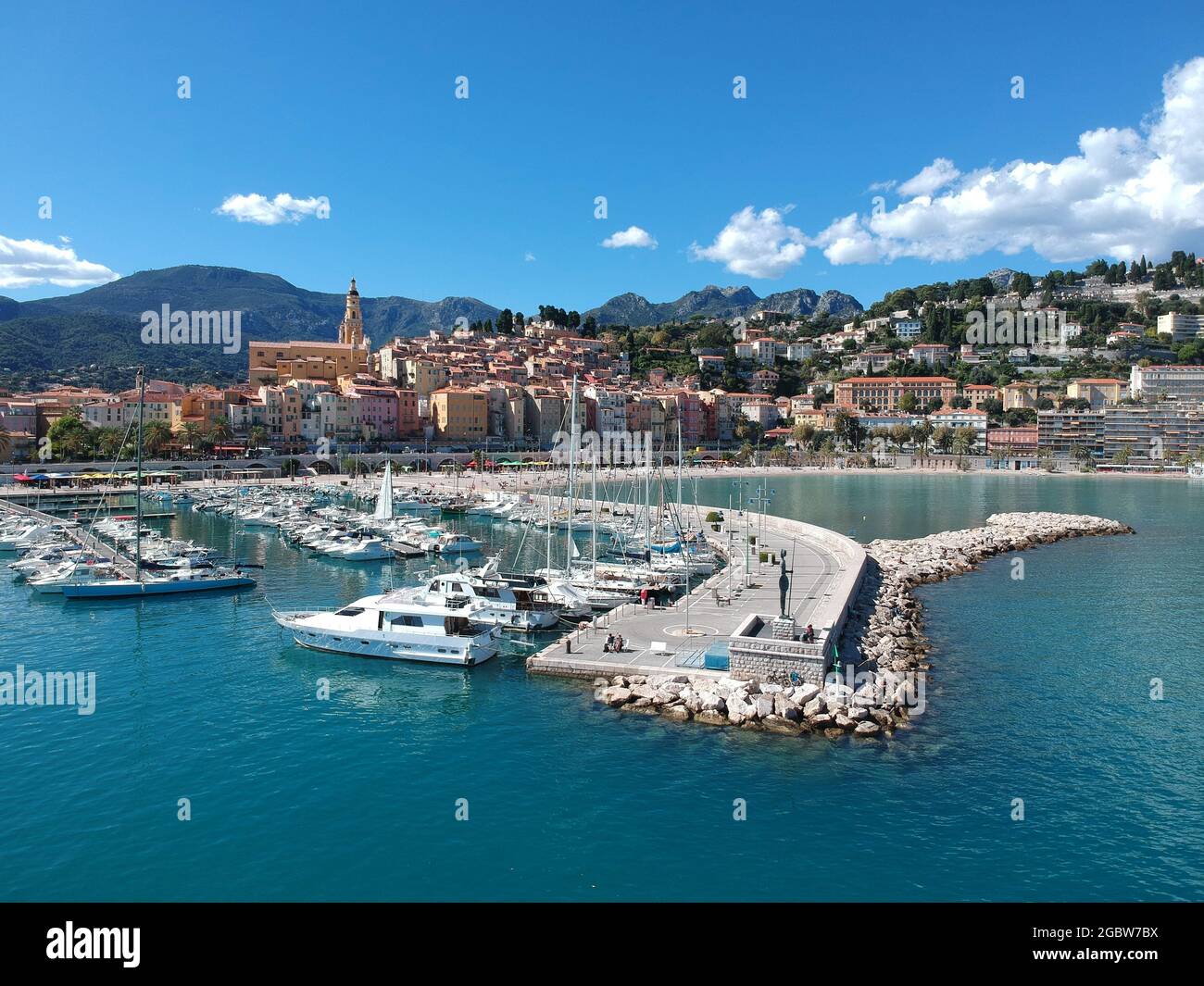 Aerial view of a beach with a port and dense buildings under a clear ...