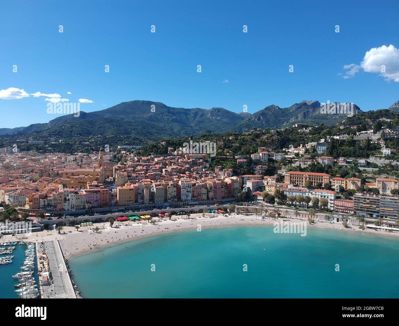 Aerial view of a beach with a port and dense buildings under a clear ...