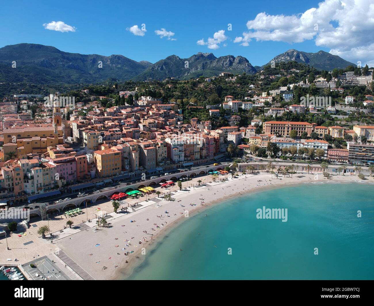Aerial view of a beach with dense buildings and hills in Menton, French ...