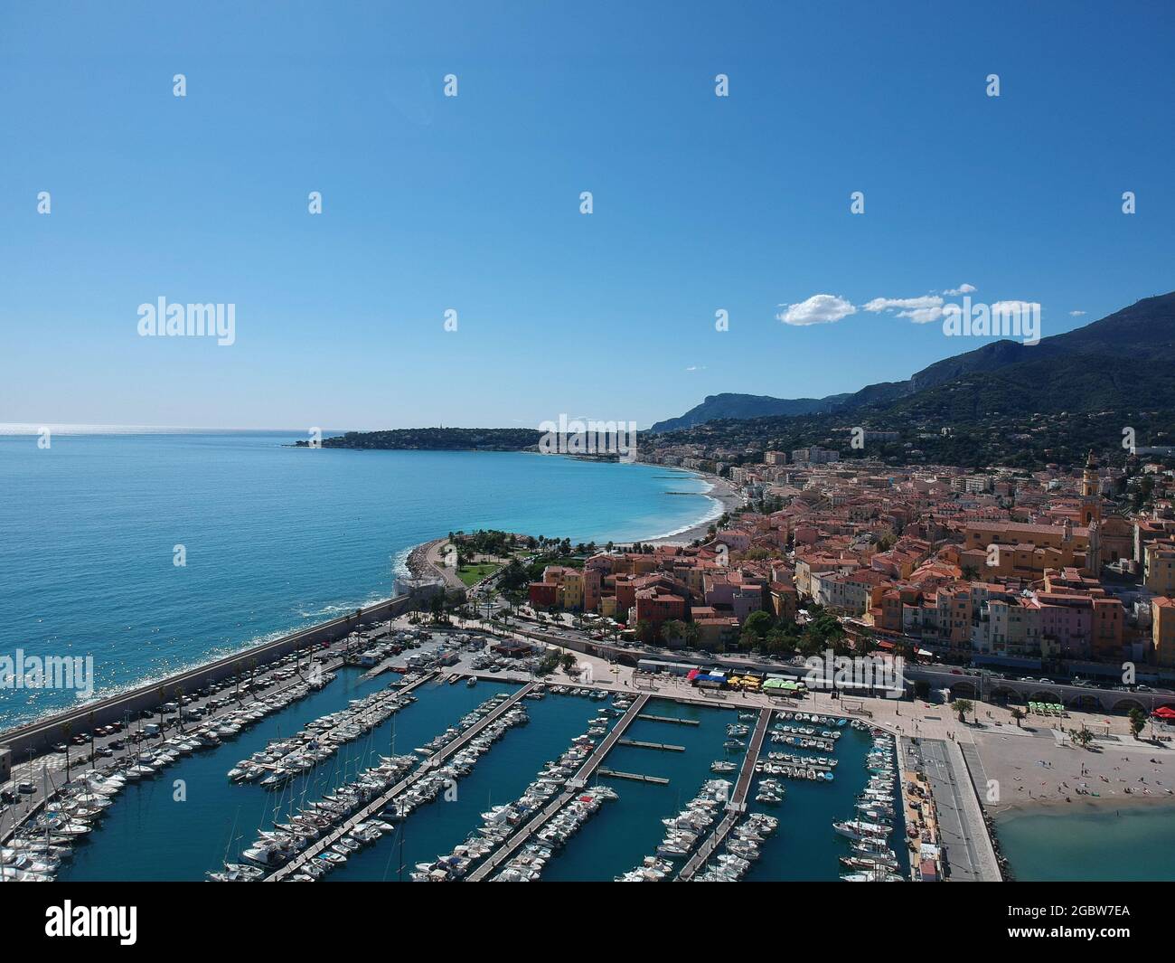 Aerial view of a beach with a port and dense buildings under a clear ...