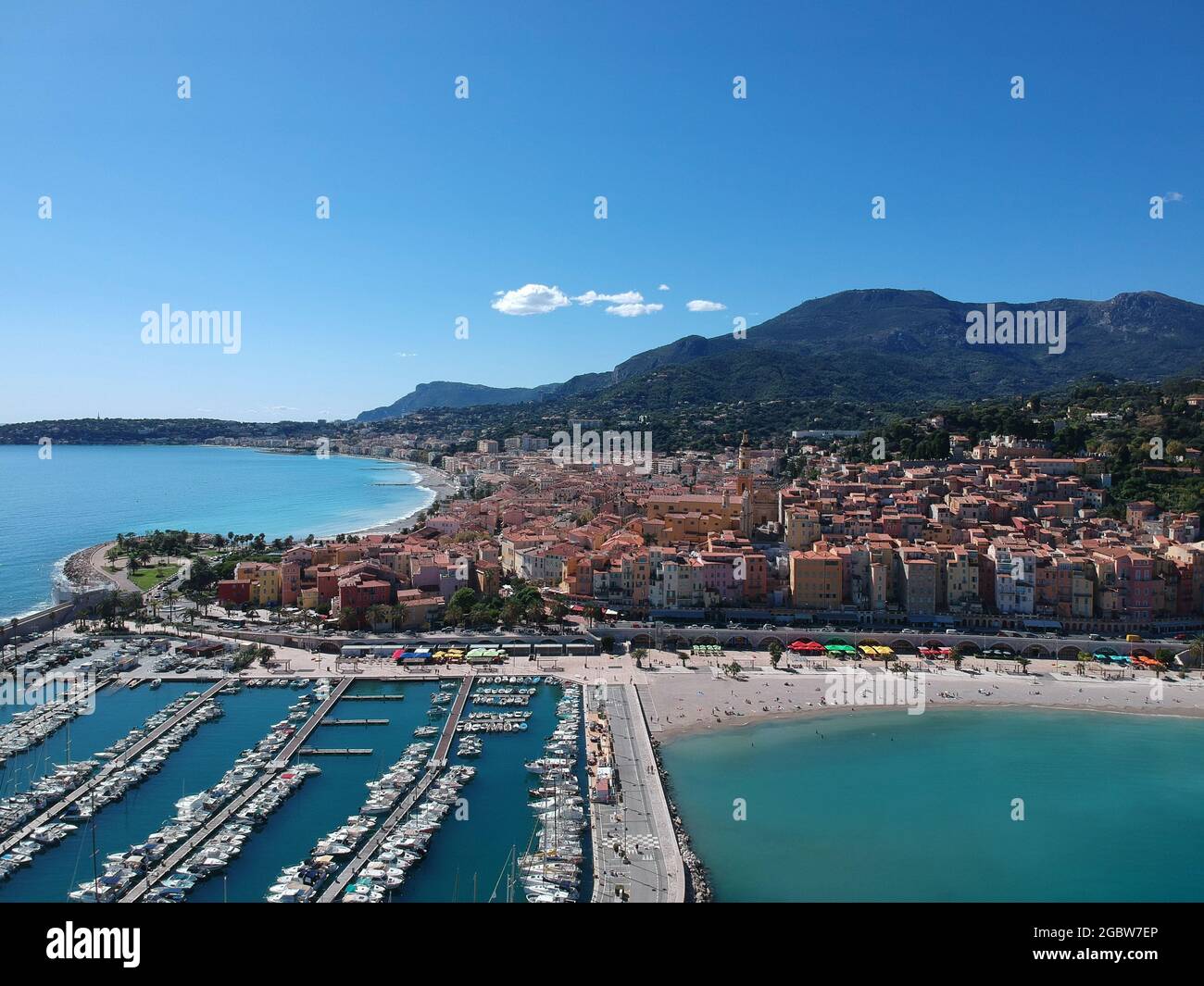 Aerial view of a beach with a port and dense buildings under a clear ...