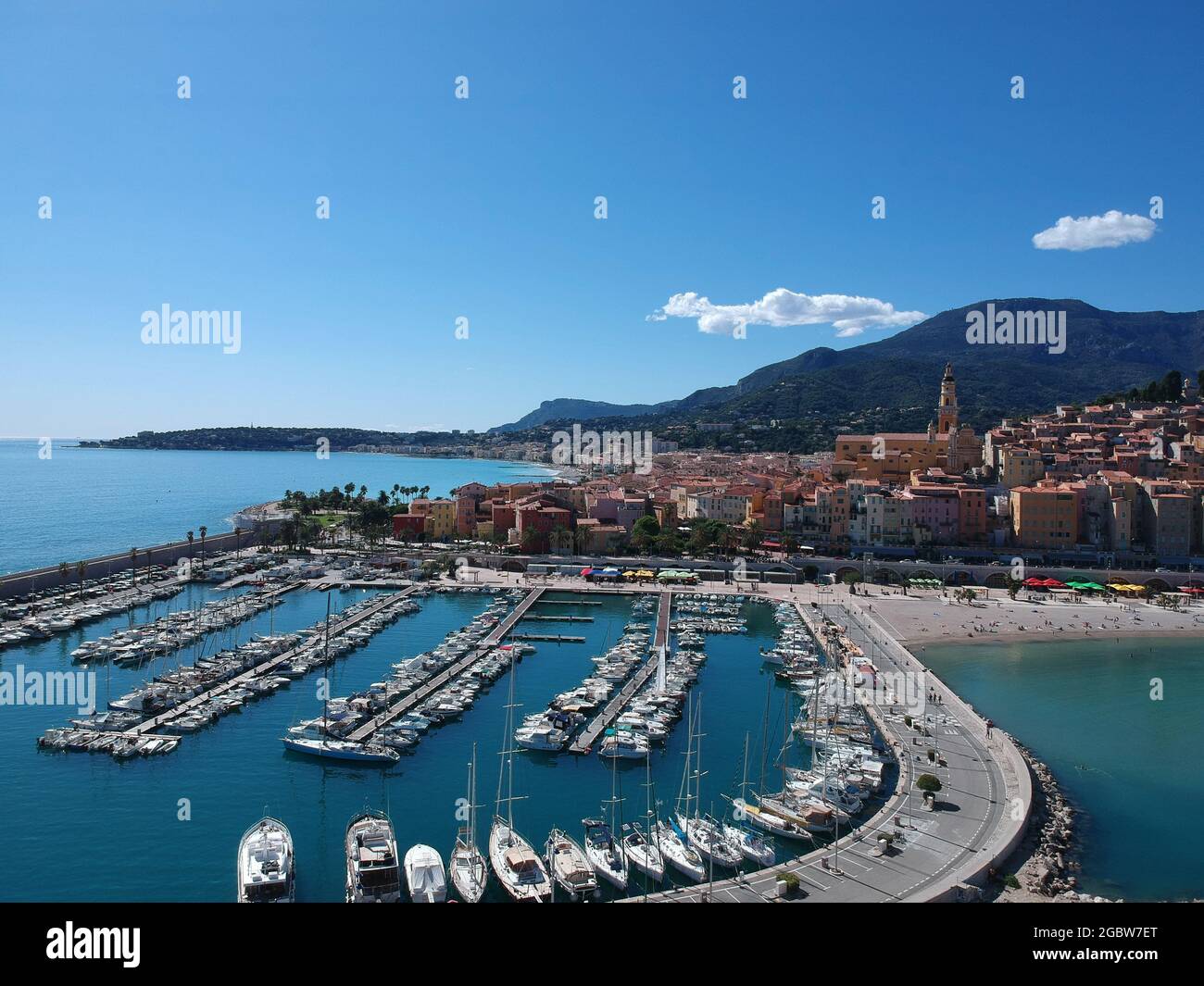 Aerial view of a beach with a port and dense buildings under a clear ...