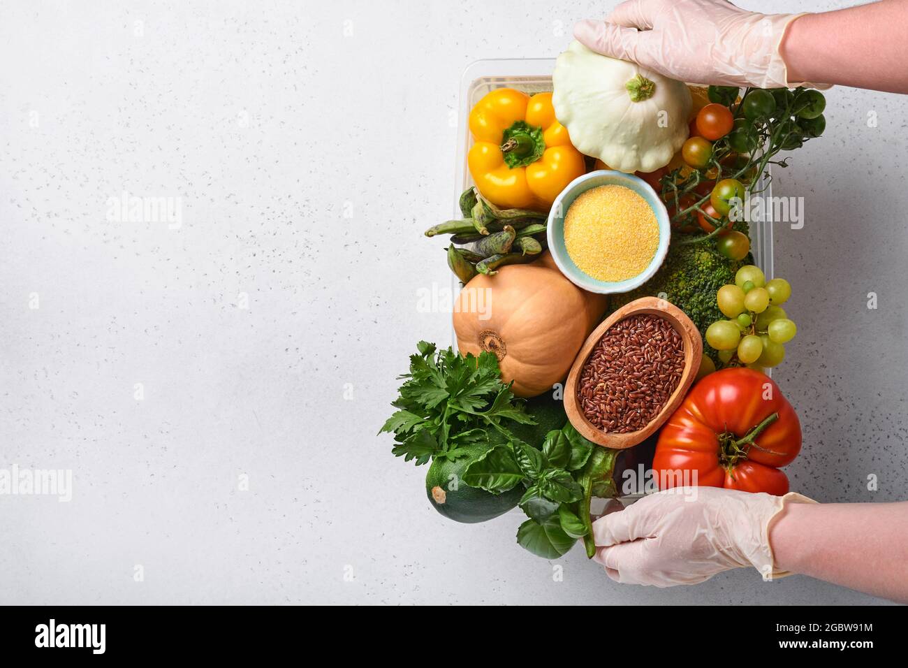 Female hands hold plastic box with assortment of fresh vegetables ...