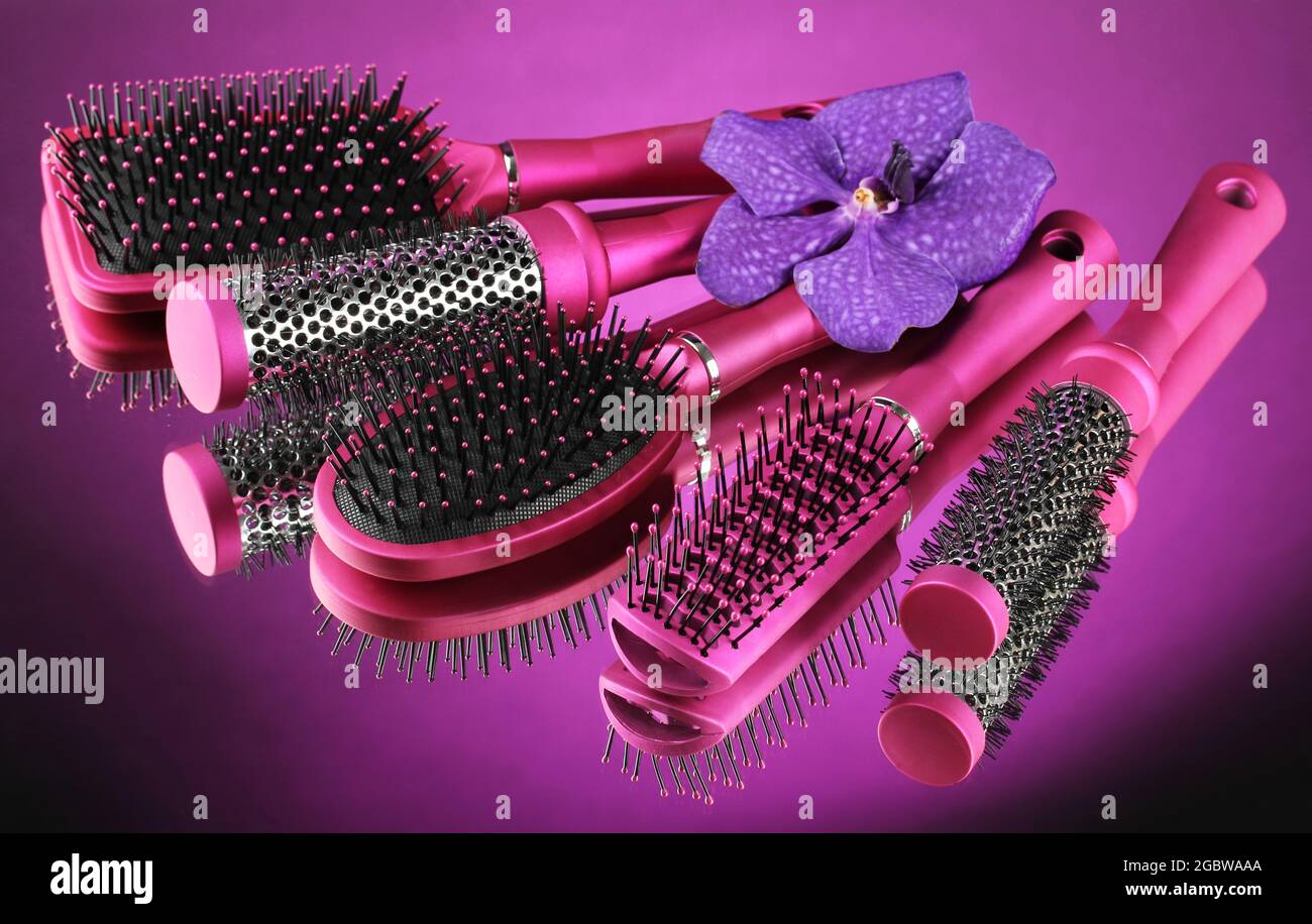 Comb brushes and flower on purple background Stock Photo - Alamy