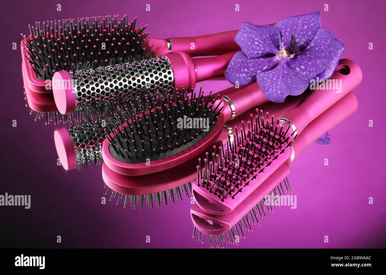 Comb brushes and flower on purple background Stock Photo - Alamy