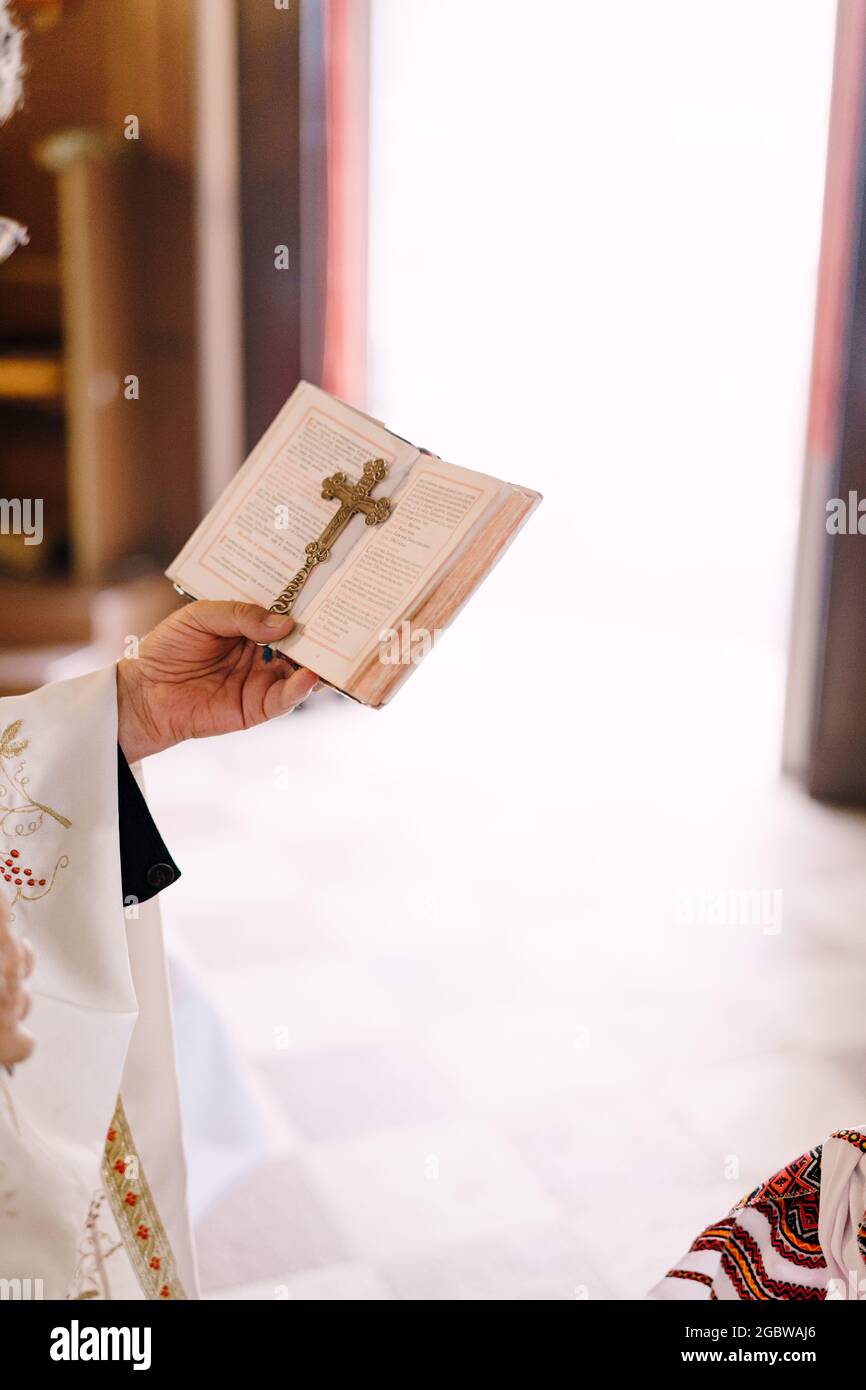 Bible and the cross in the hand of the priest. Close-up Stock Photo - Alamy