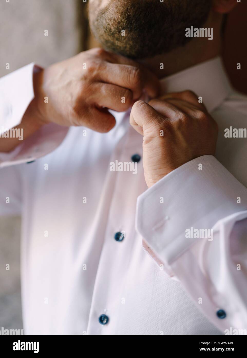 Groom buttons the collar of his white shirt. Close-up Stock Photo - Alamy