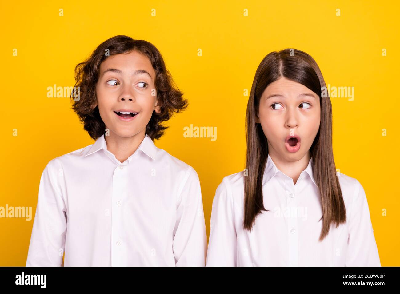 Photo of impressed sweet schoolkids formalwear big eyes looking each ...