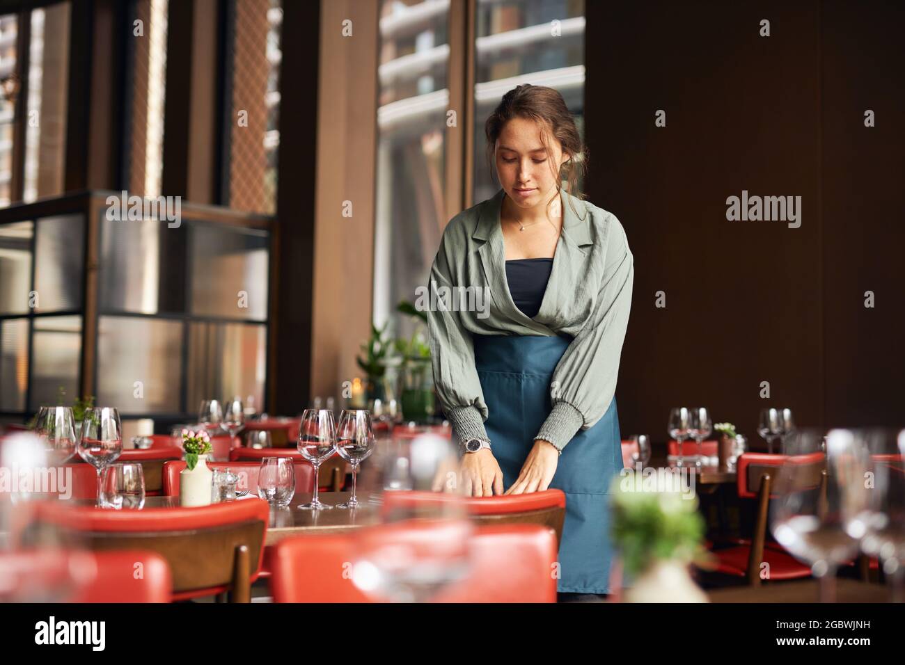 Female restaurant owner setting tables Stock Photo - Alamy