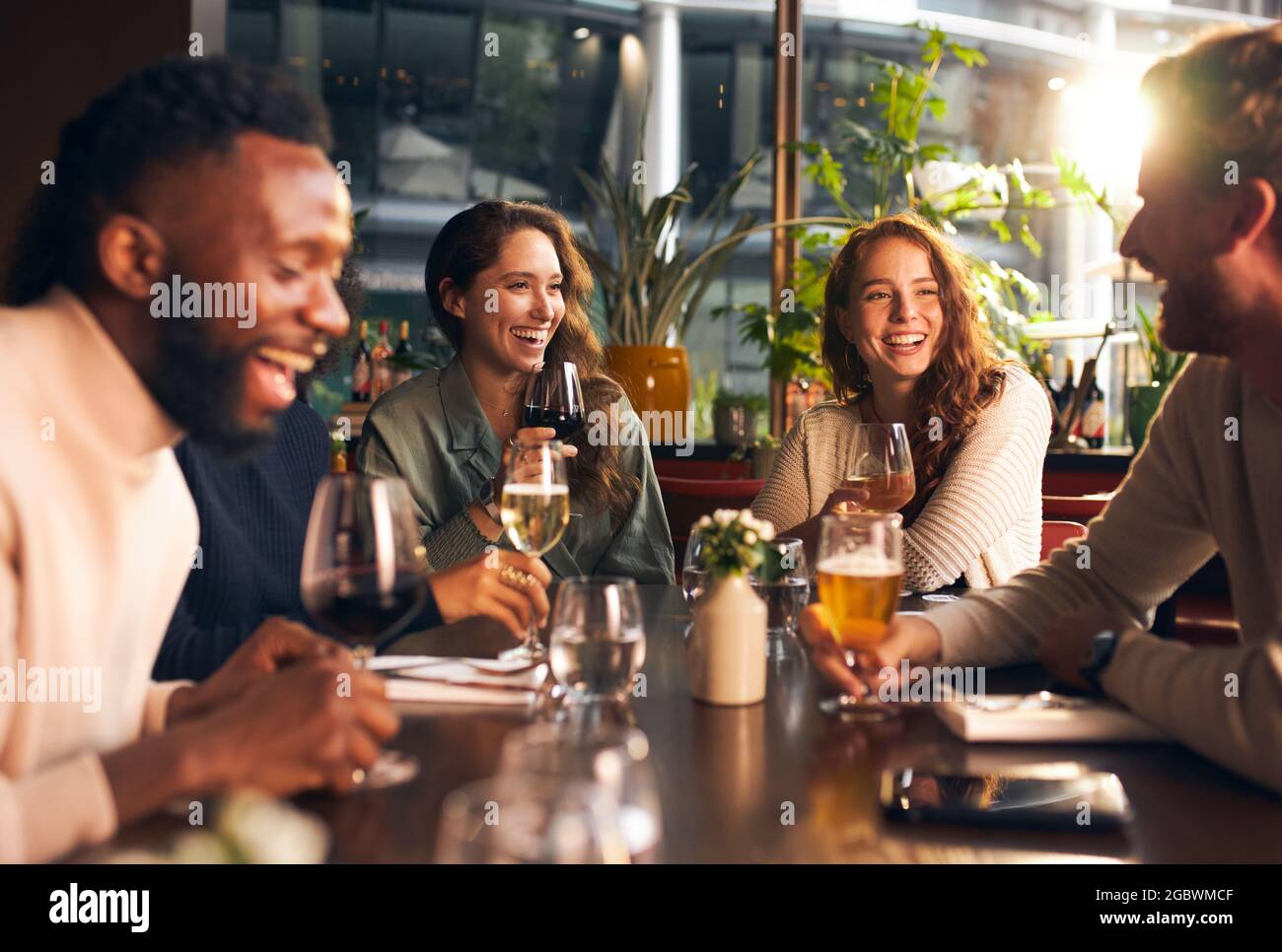 Friends laughing with drinks in bar Stock Photo - Alamy