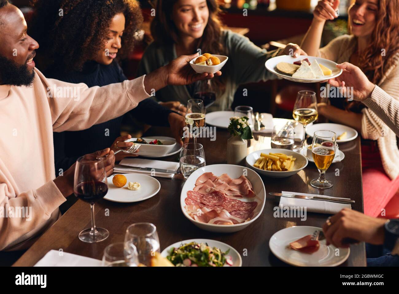 Friends sharing plates of food in restaurant Stock Photo - Alamy
