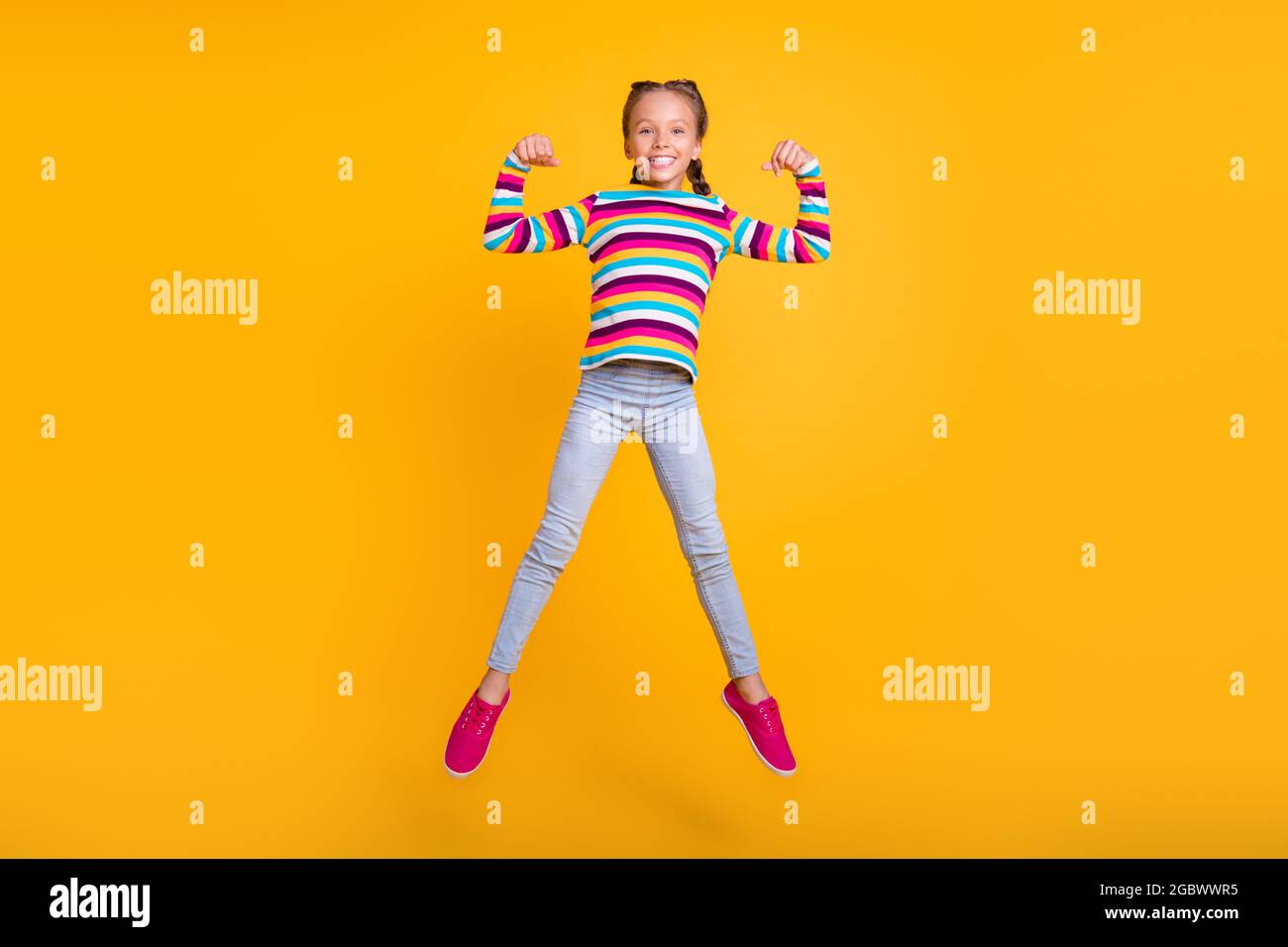 Photo of small girl jump show two strong biceps wear striped shirt ...