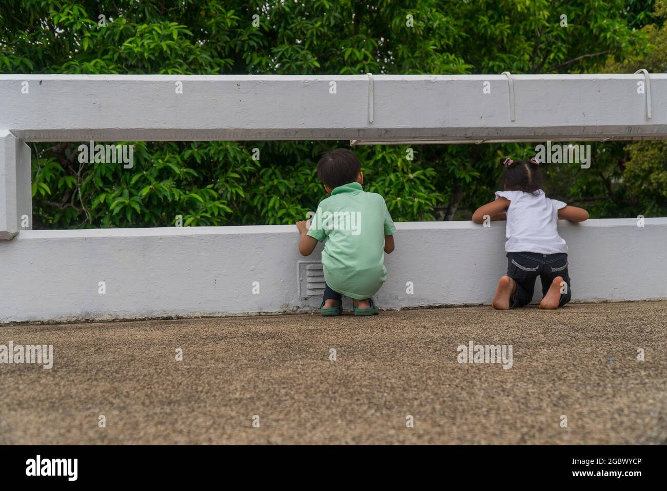 Little asian kids stand on the bridge, leaning on the fence Stock Photo ...
