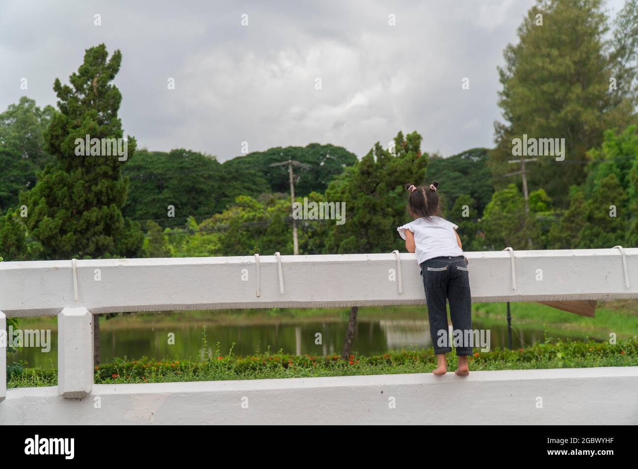Little asian kids stand on the bridge, leaning on the fence Stock Photo ...