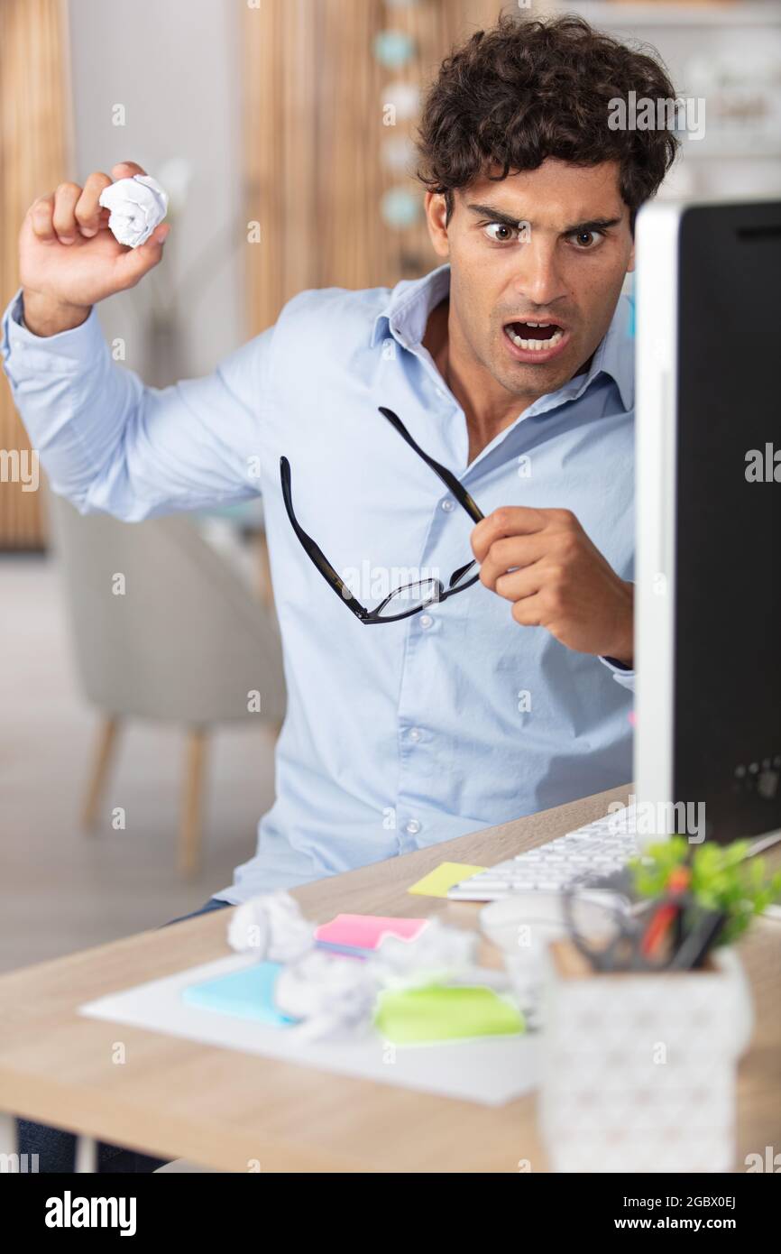 angry man using a computer throwing screwed up paper Stock Photo - Alamy