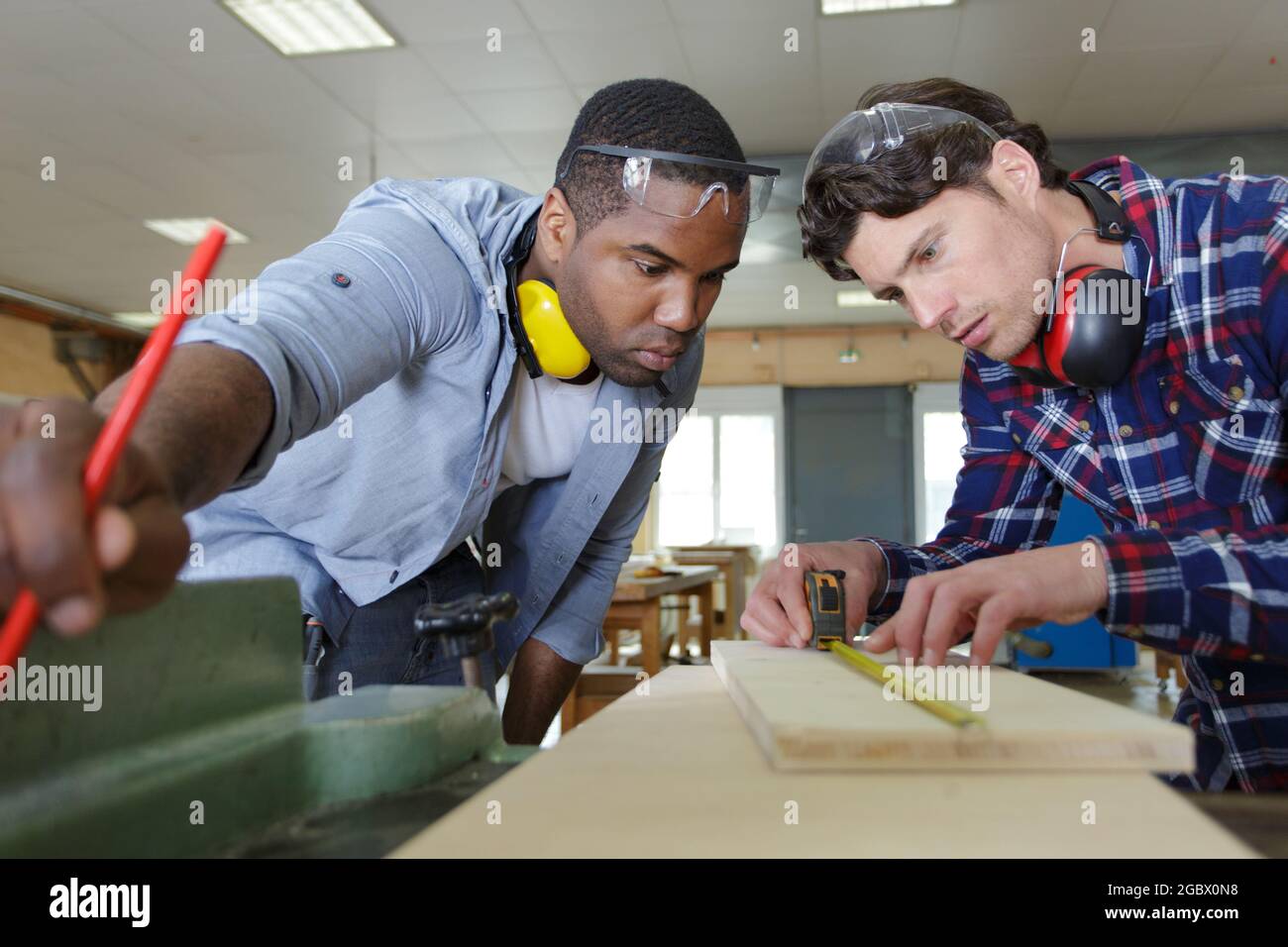 two male carpenters measuring wood in the workshop Stock Photo - Alamy