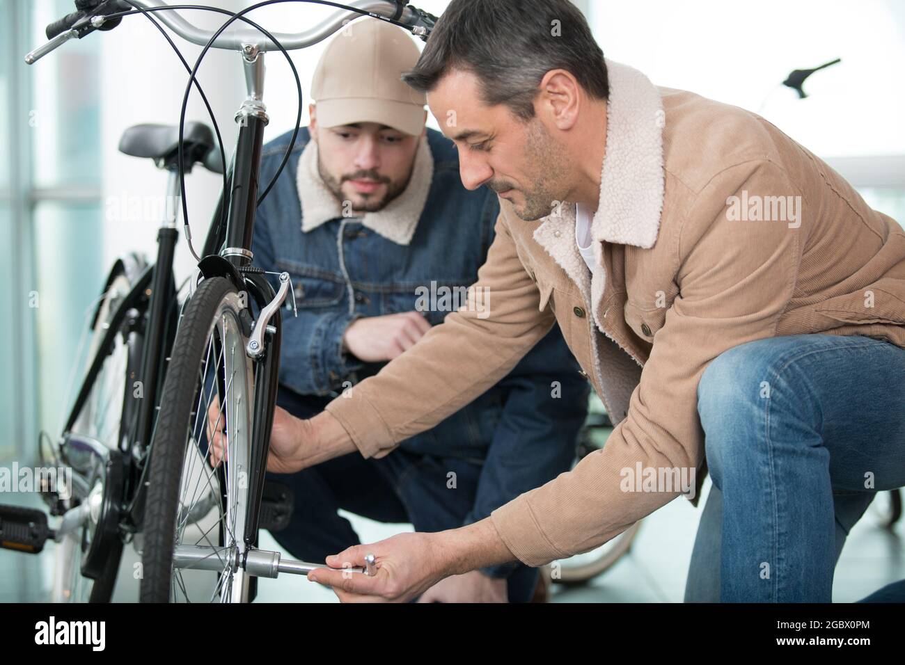 men adjusting bicycle chain indoors Stock Photo - Alamy