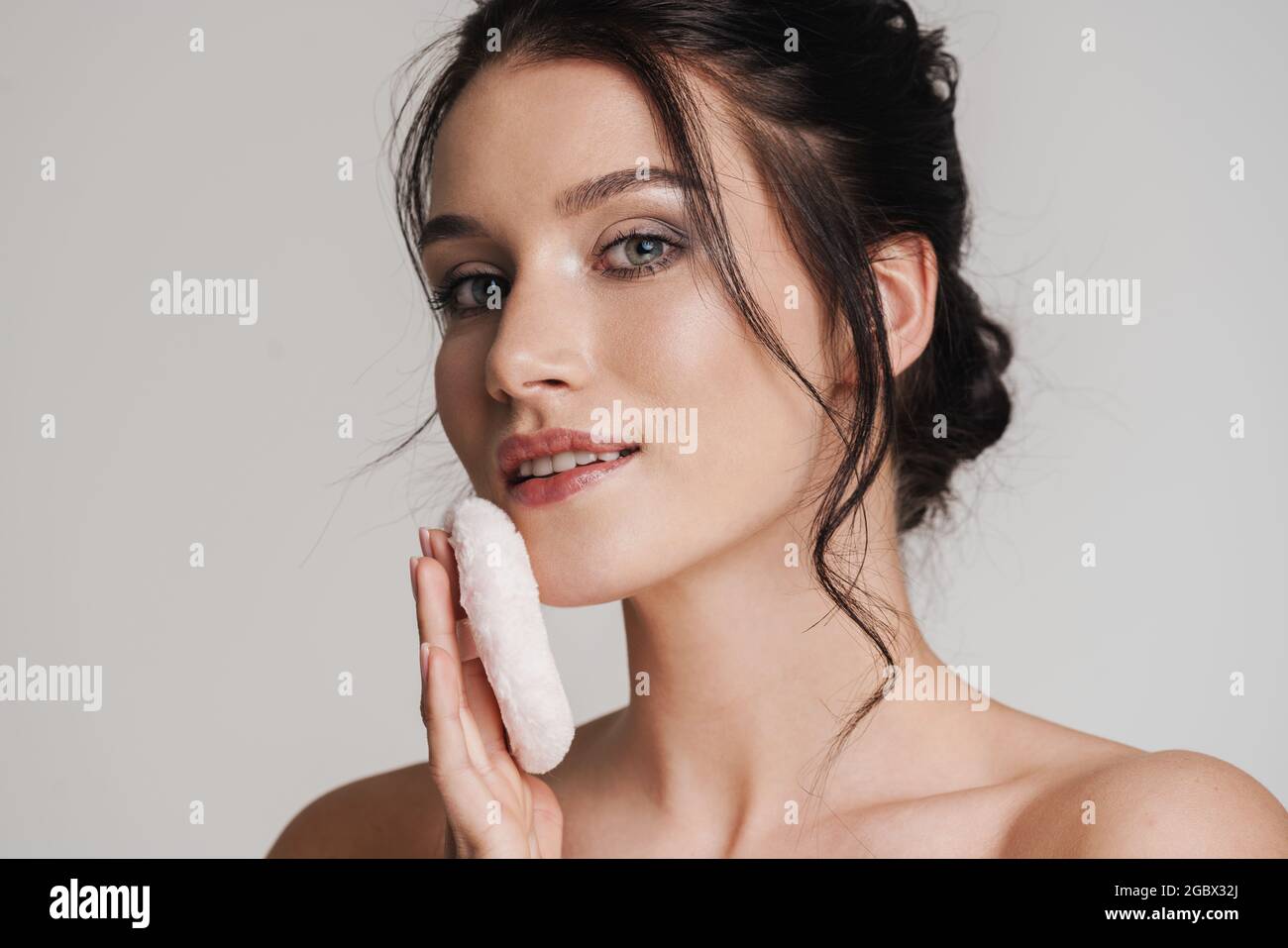 Young white woman with brown hair pulled up holding powder puff ...