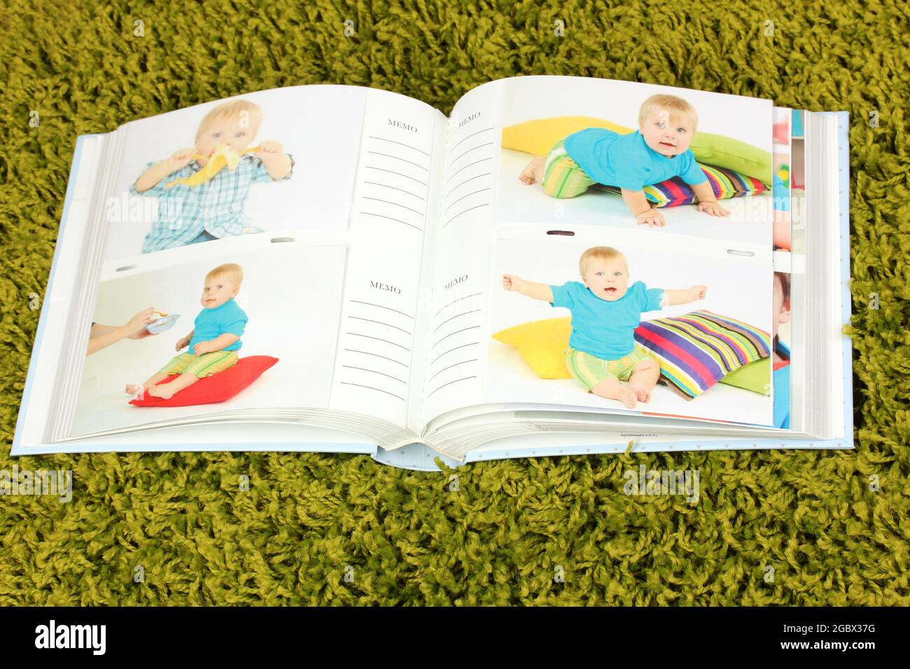 Open photo album with pictures on green carpet Stock Photo - Alamy