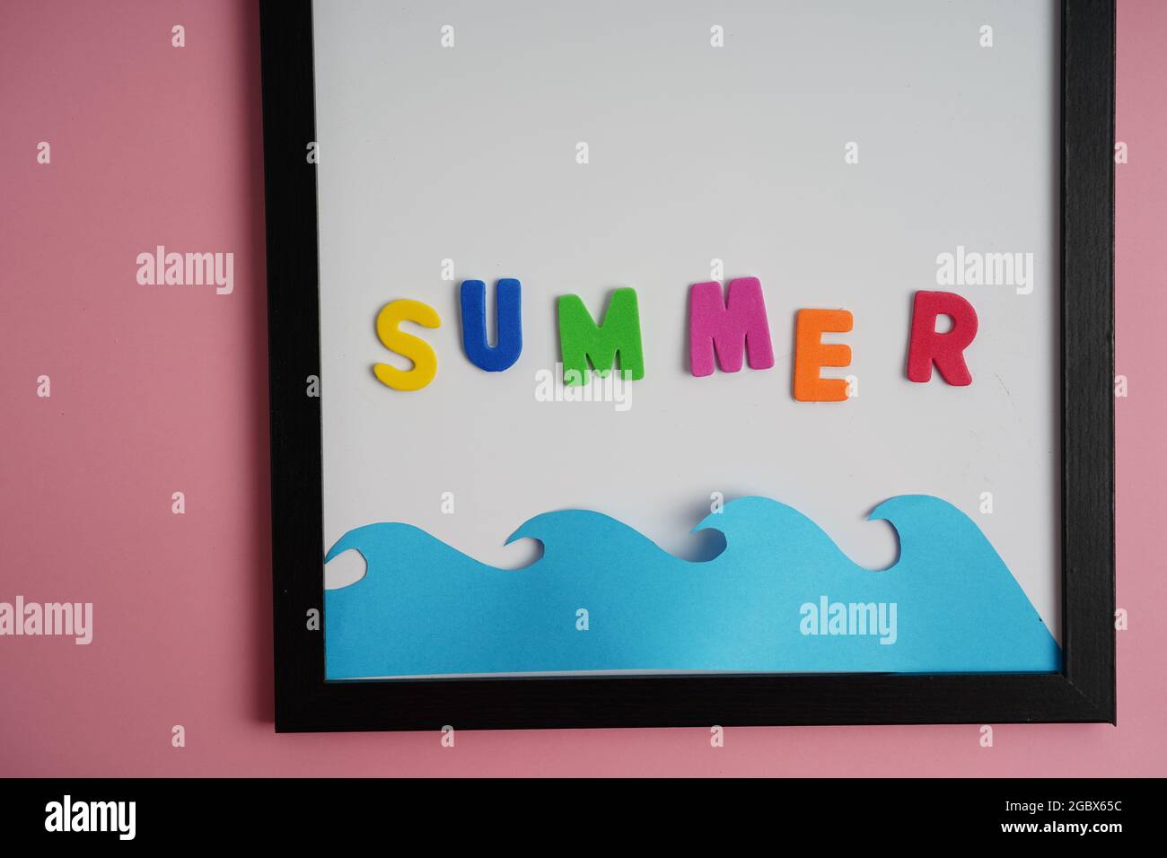 Word summer written in colored alphabets on a frame with a pink ...