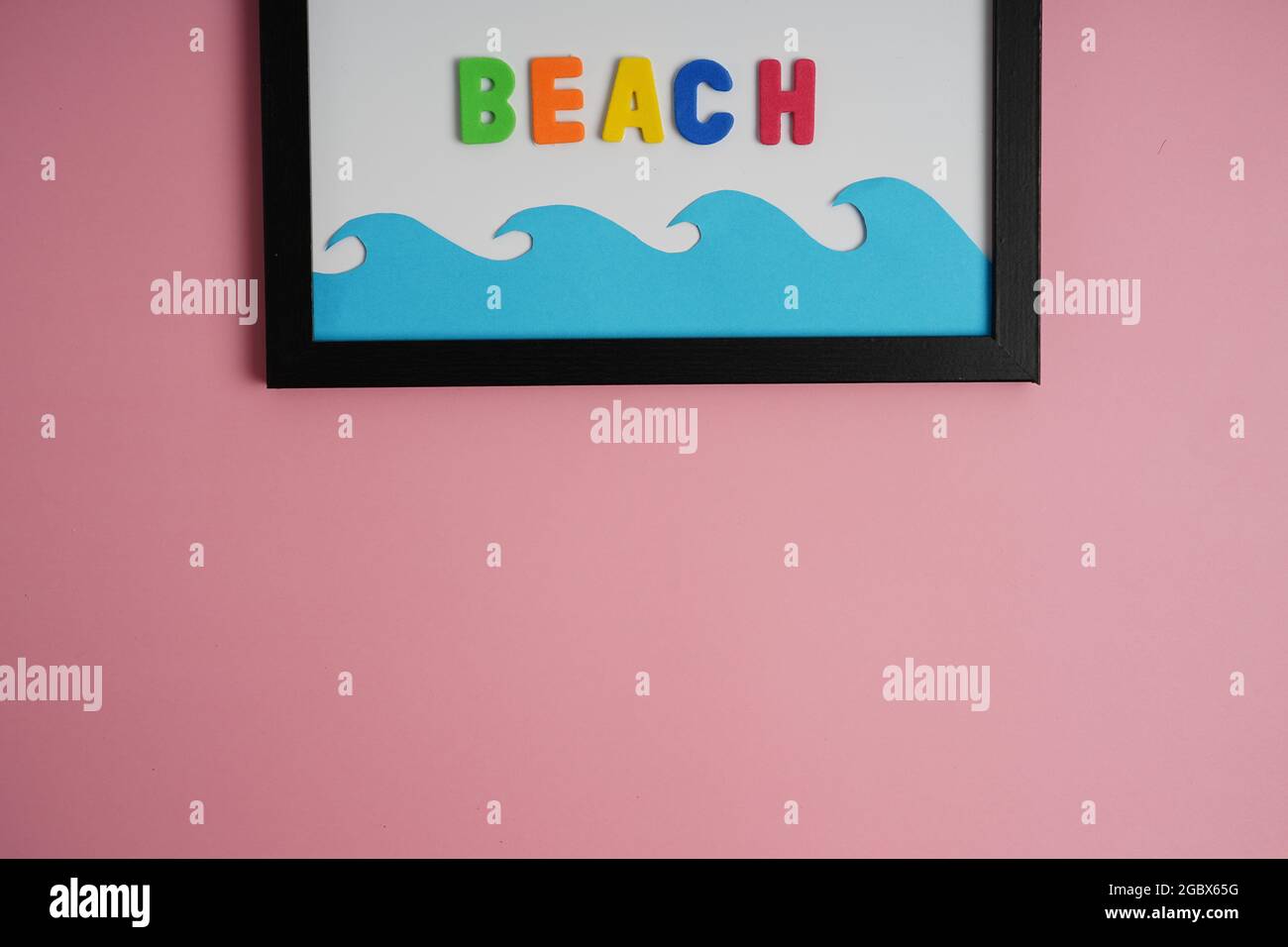 Word beach written in colored alphabets on a frame with a pink ...