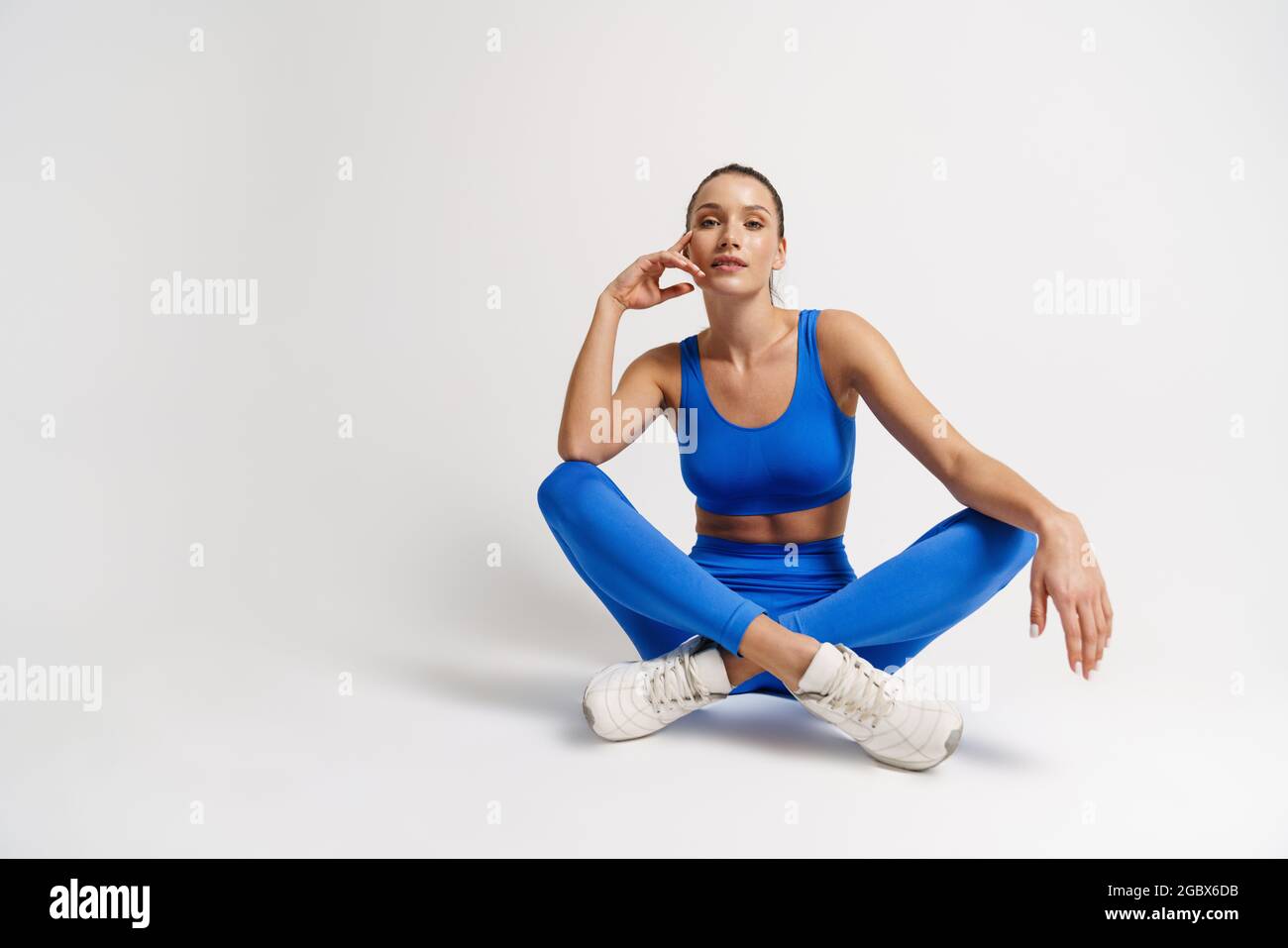 Young white fitness woman in sportswear with ponytail sitting on a ...