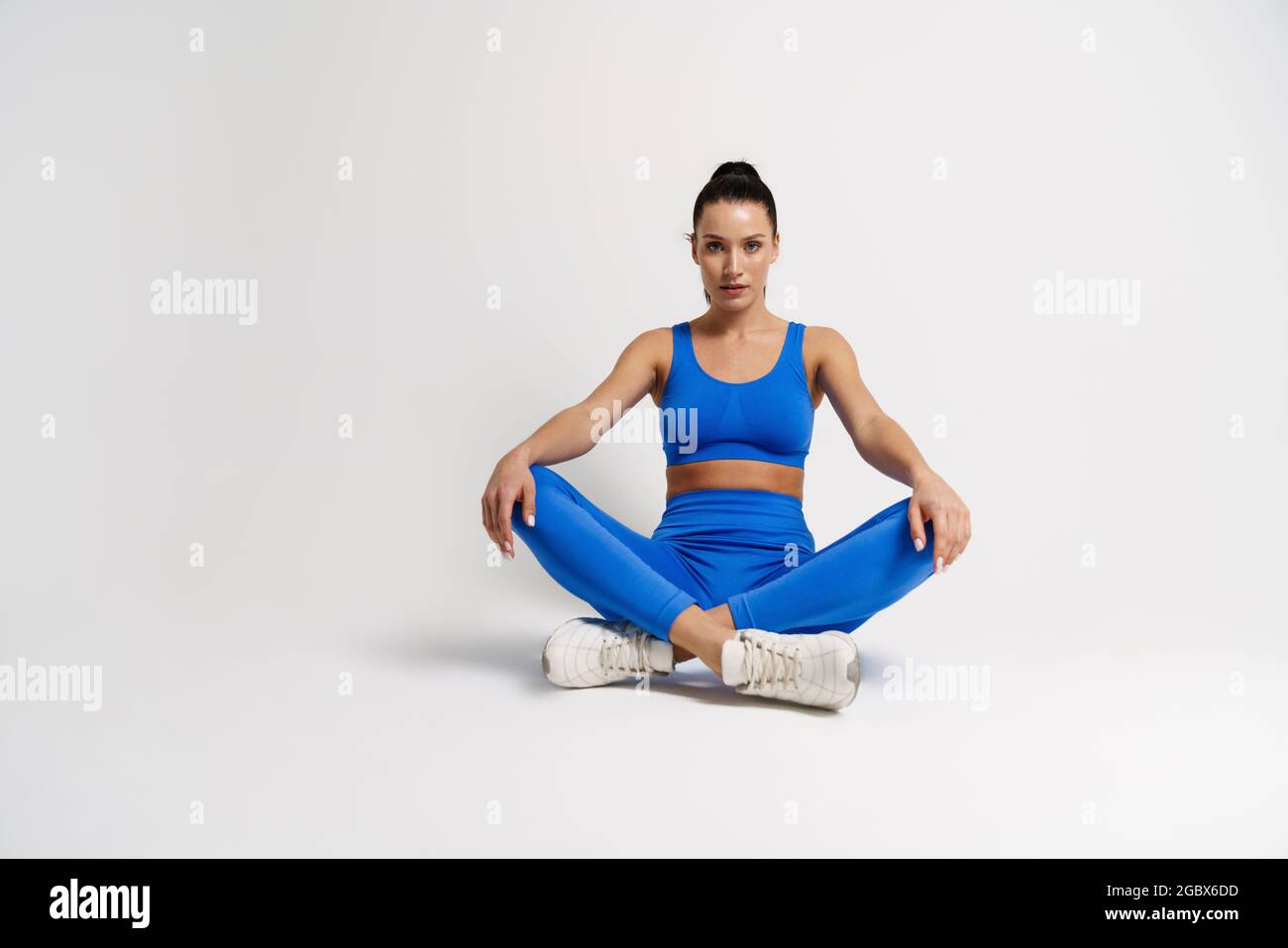 Young white fitness woman in sportswear with ponytail sitting on a ...
