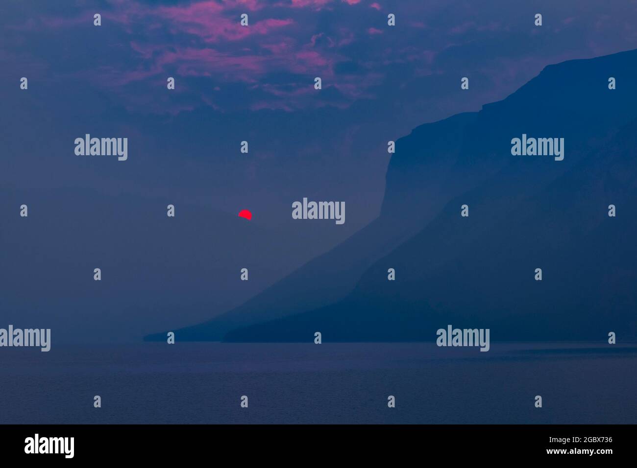 Red sun in smoky sunrise, Lake Minnewanka, Banff National Park, Alberta ...