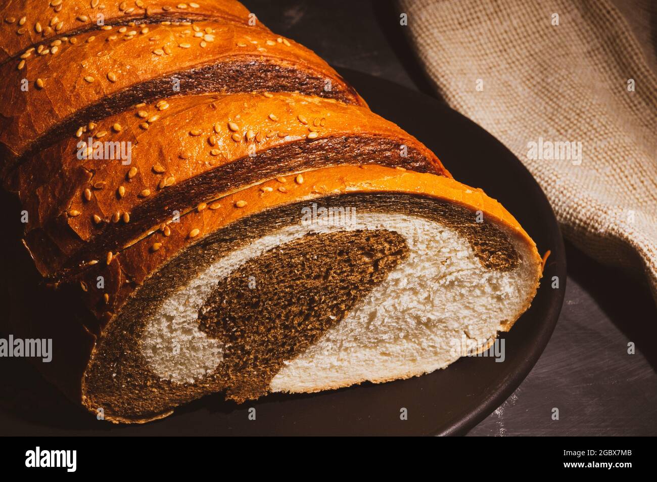 Unusual two-color fresh loaf of bread in a ceramic plate and a woven ...