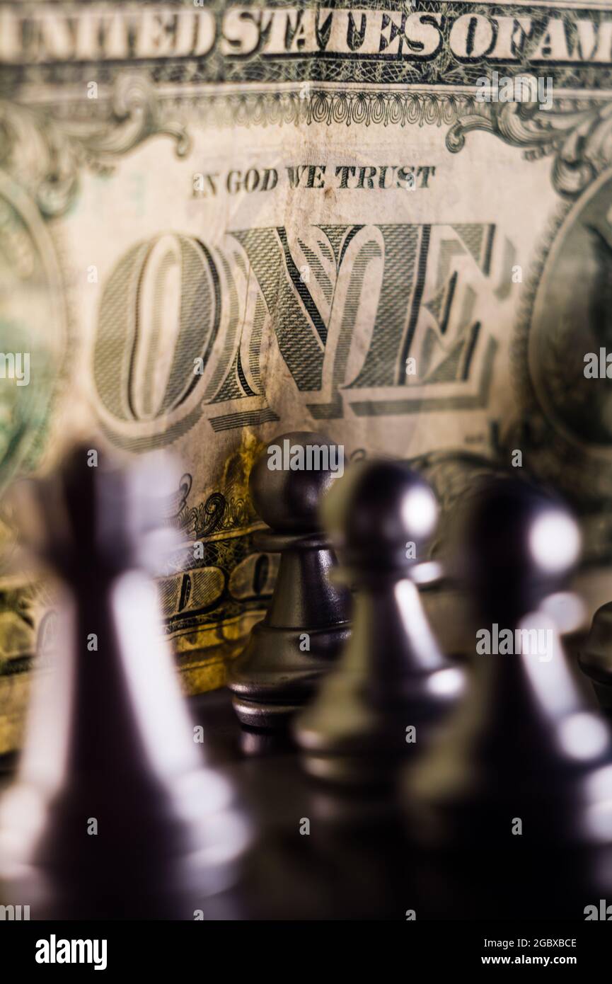 Vertical shot of a dollar bill on a chessboard with chess figurines ...