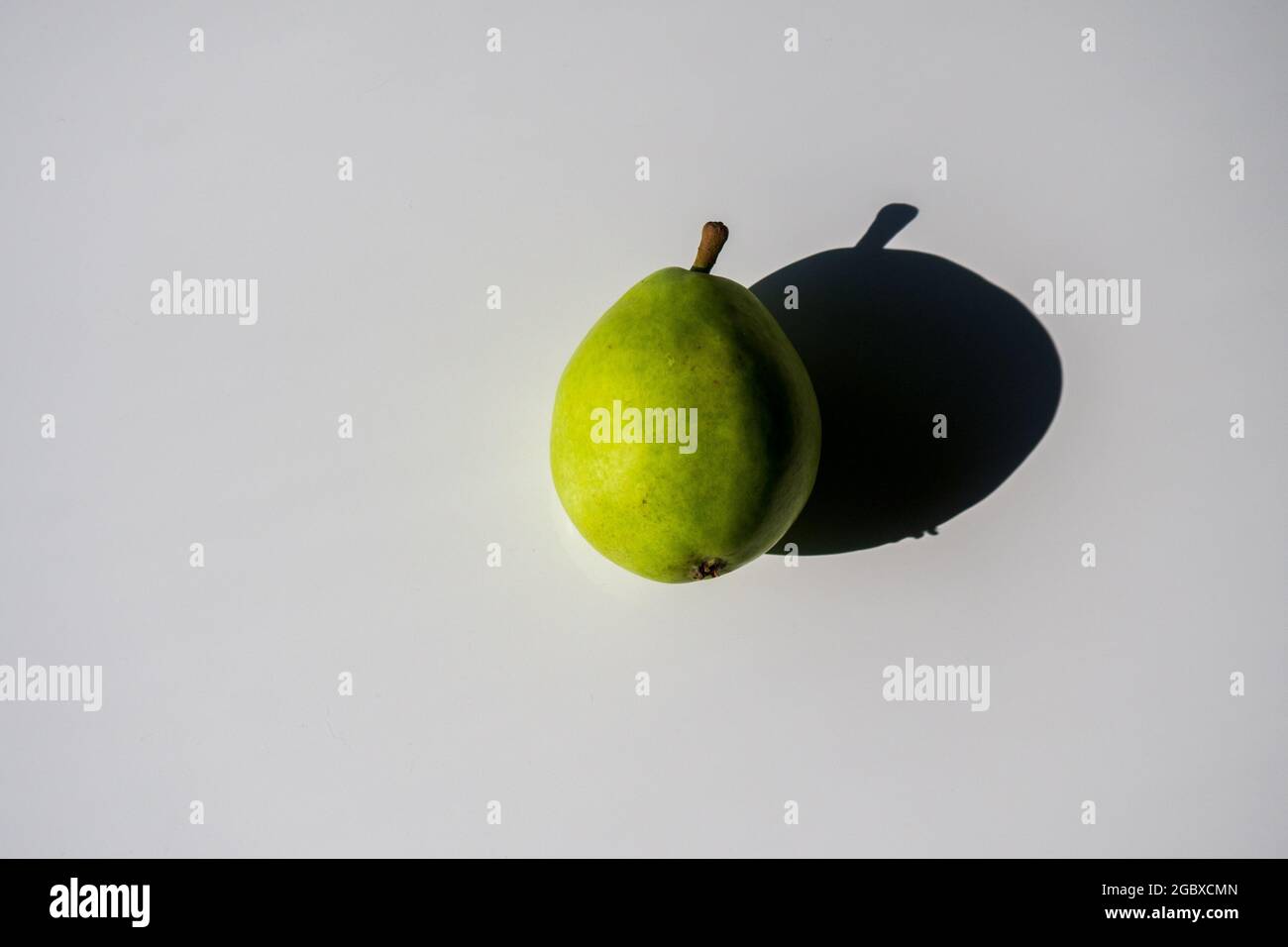 A pear and its shadow on a white background Stock Photo - Alamy