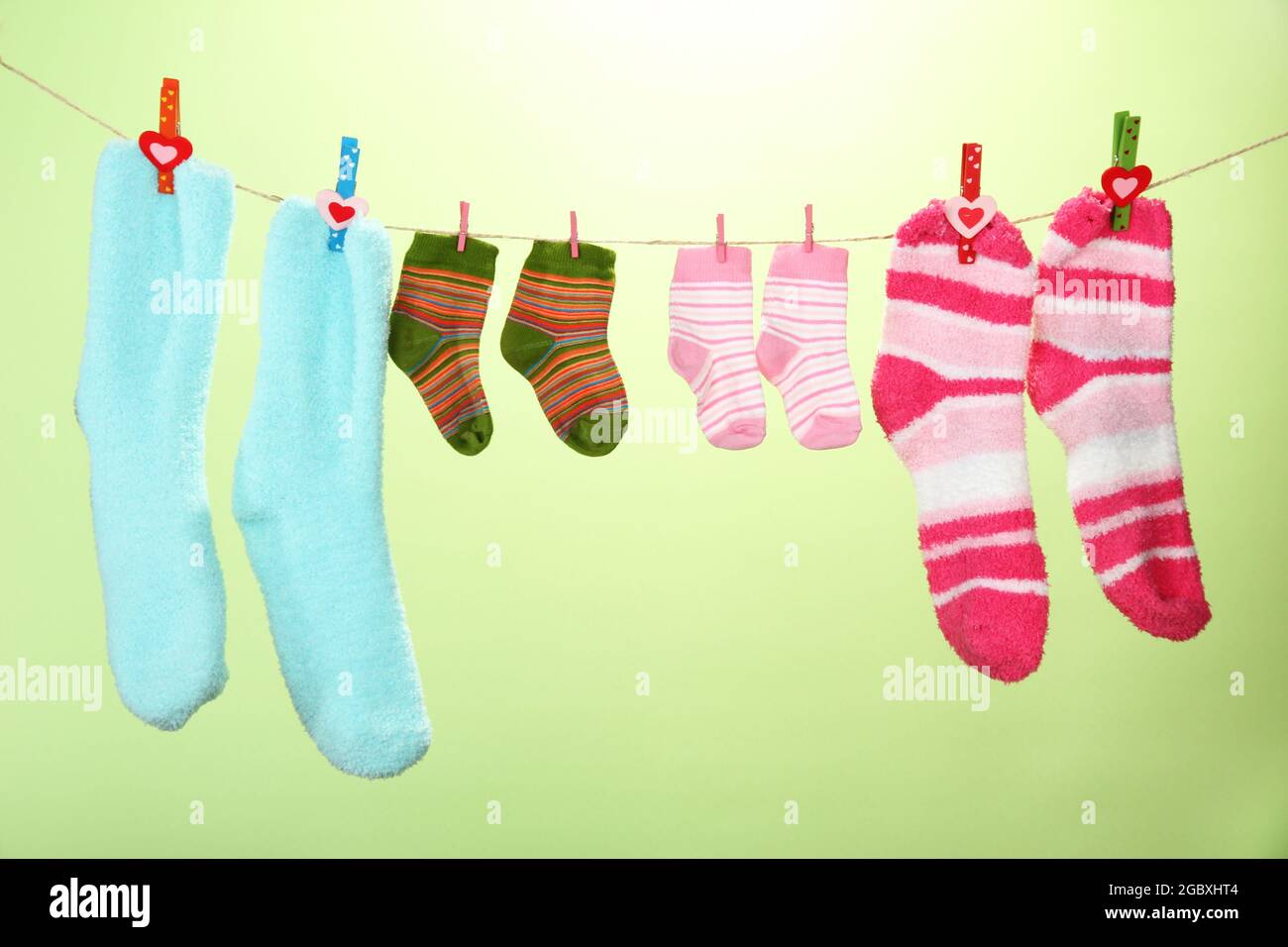 Colorful socks hanging on clothesline, on color background Stock Photo ...